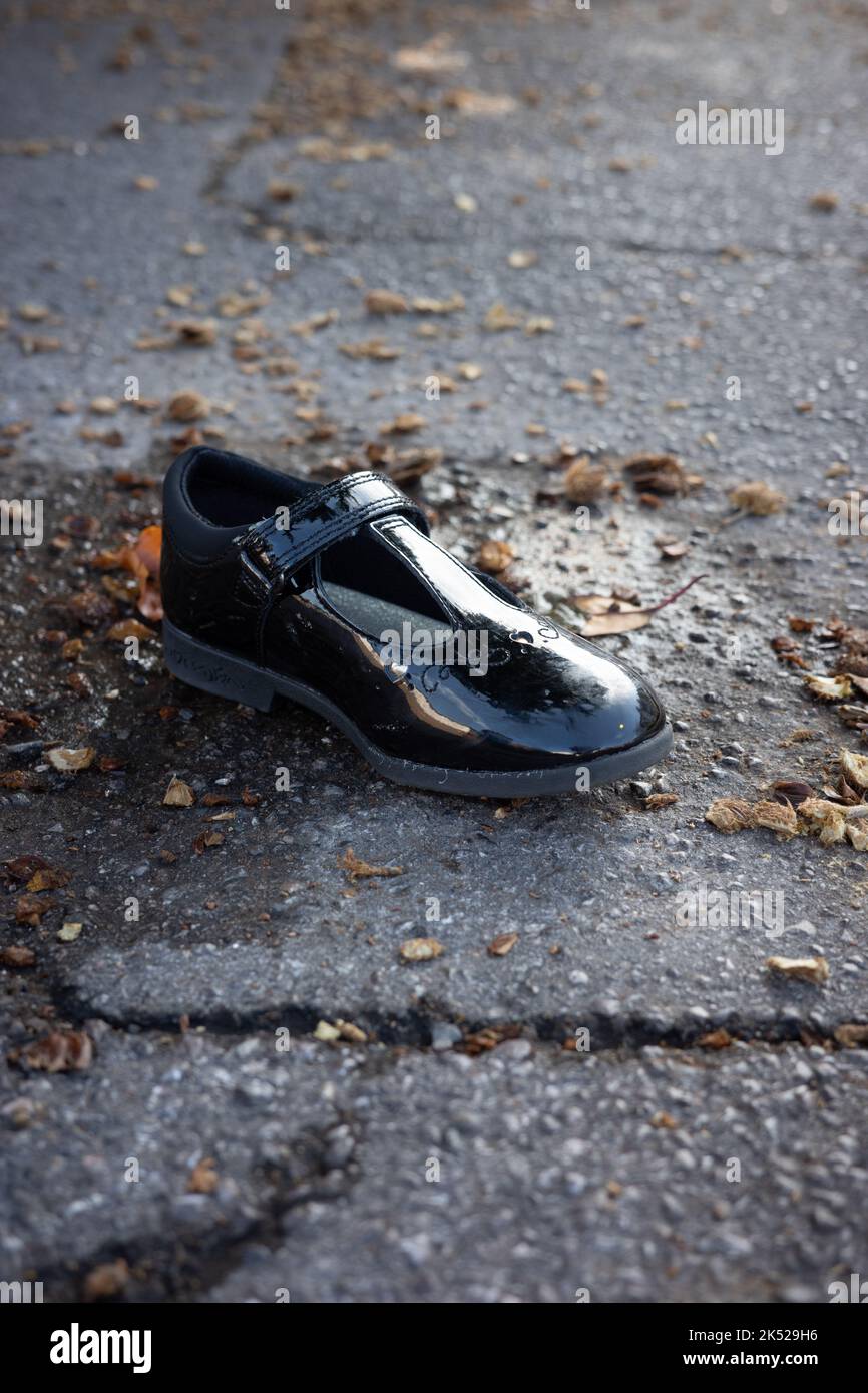 Single black child shoe left abandoned on the path Stock Photo - Alamy