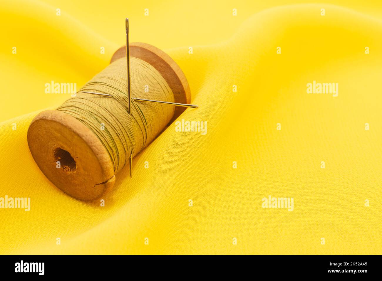 Old retro sewing accessories lie on a yellow fabric. Needle and thread ...