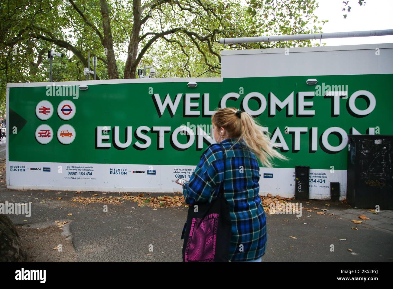 A woman walks past a 'Welcome to Euston Station' sign Stock Photo - Alamy