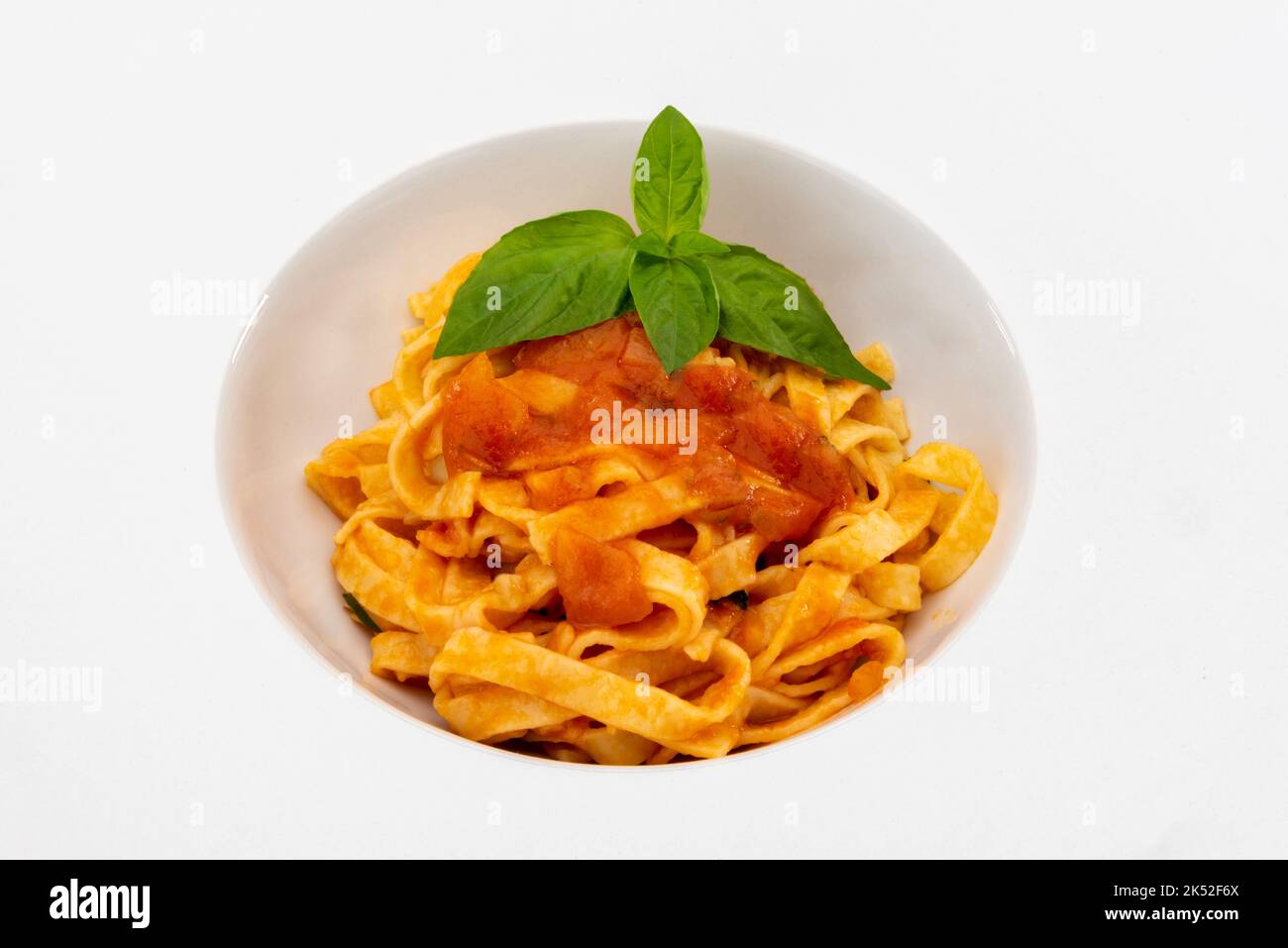 Egg pasta tagliatelle with tomato sauce and basil leaves in white plate ...