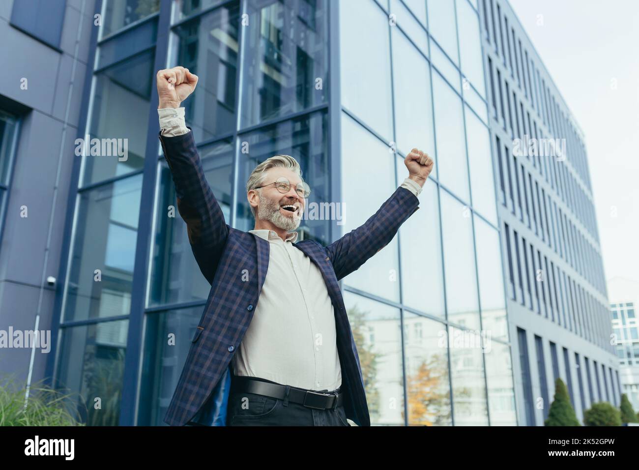 Successful and happy gray-haired boss outside office building rejoices ...