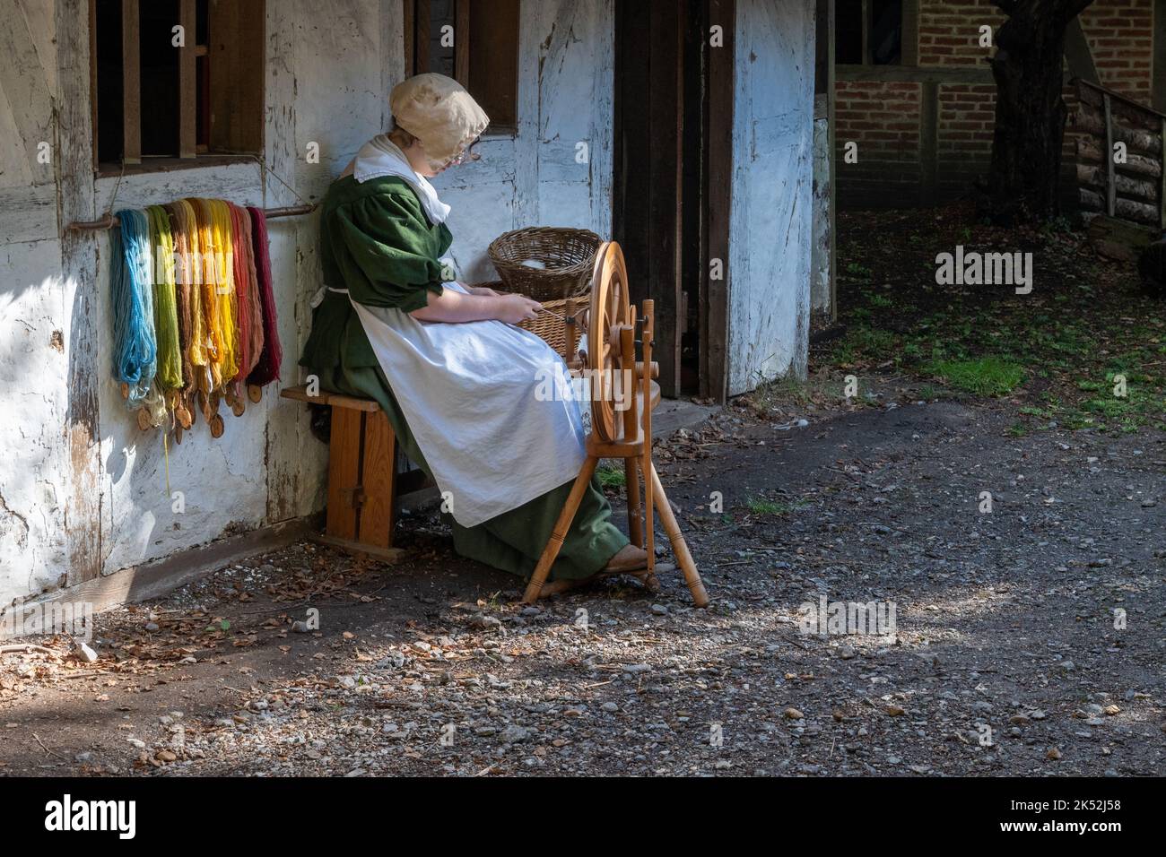 Woman in traditional costume spinning cotton on a traditional spinning ...