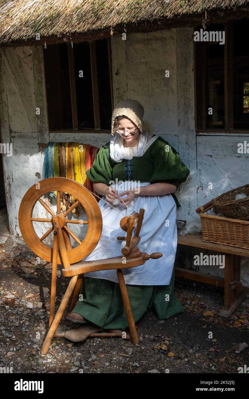 Woman in traditional costume spinning cotton on a traditional spinning ...