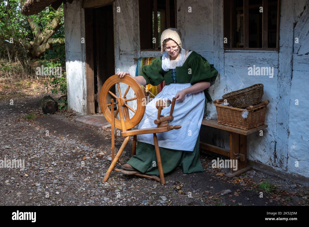Woman in traditional costume spinning cotton on a traditional spinning ...