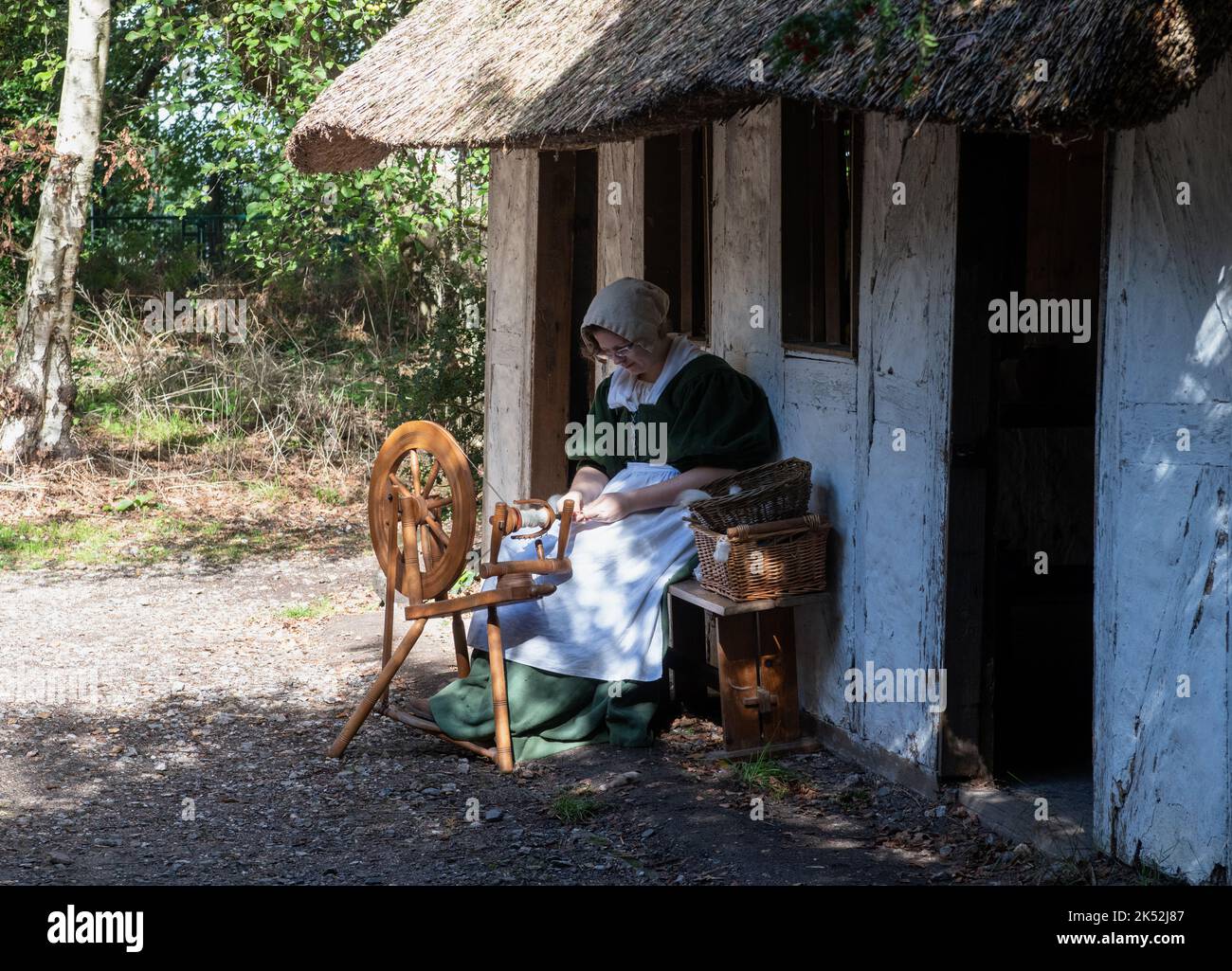 Woman in traditional costume spinning cotton on a traditional spinning ...