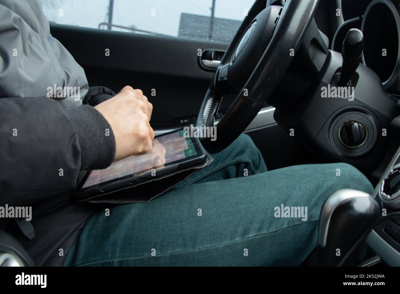 sales representative driving his car with a tablet in his hands, hands ...