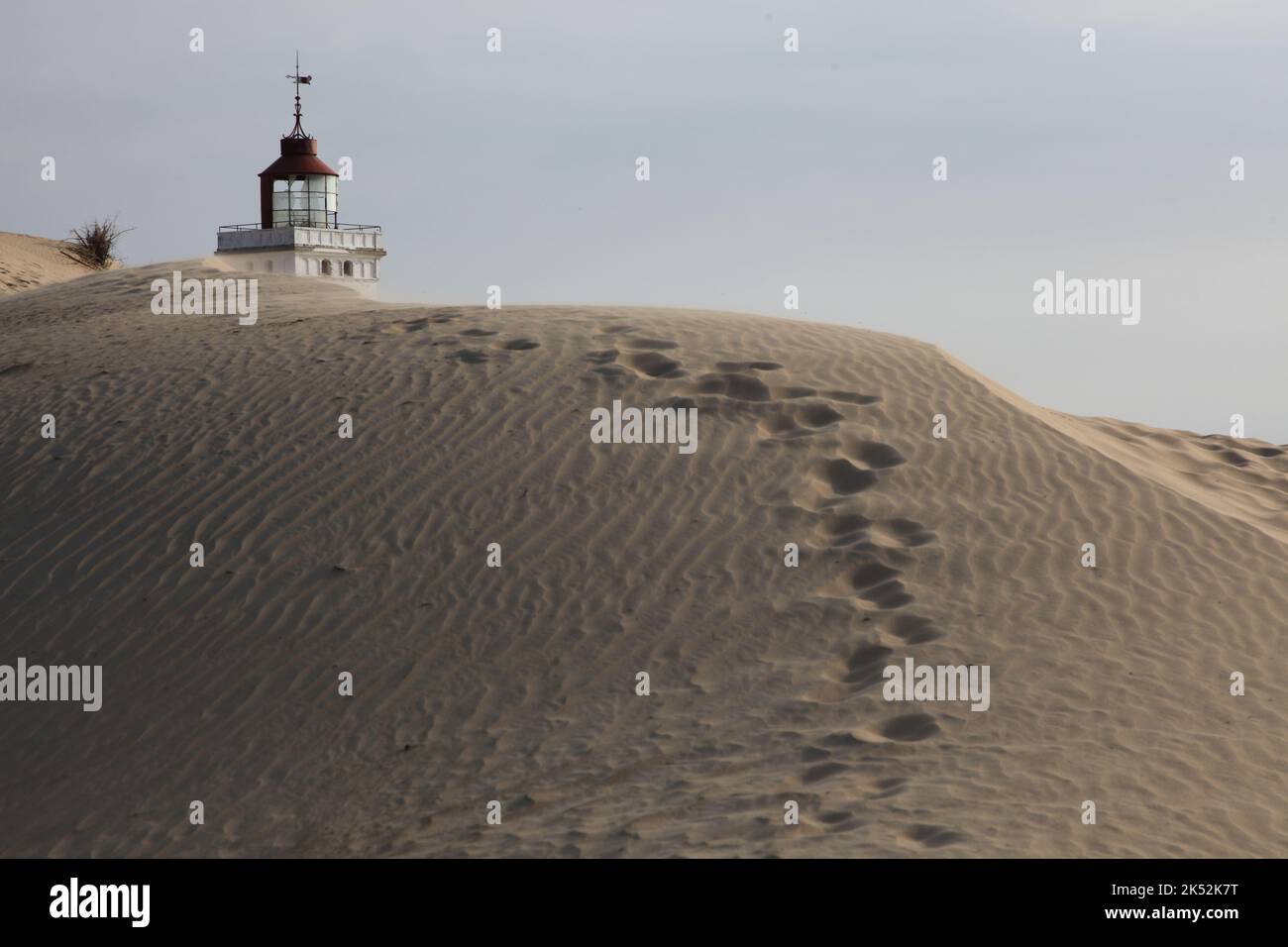 A scenic view of Rubjerg Knude Lighthouse behind a desert dune in ...