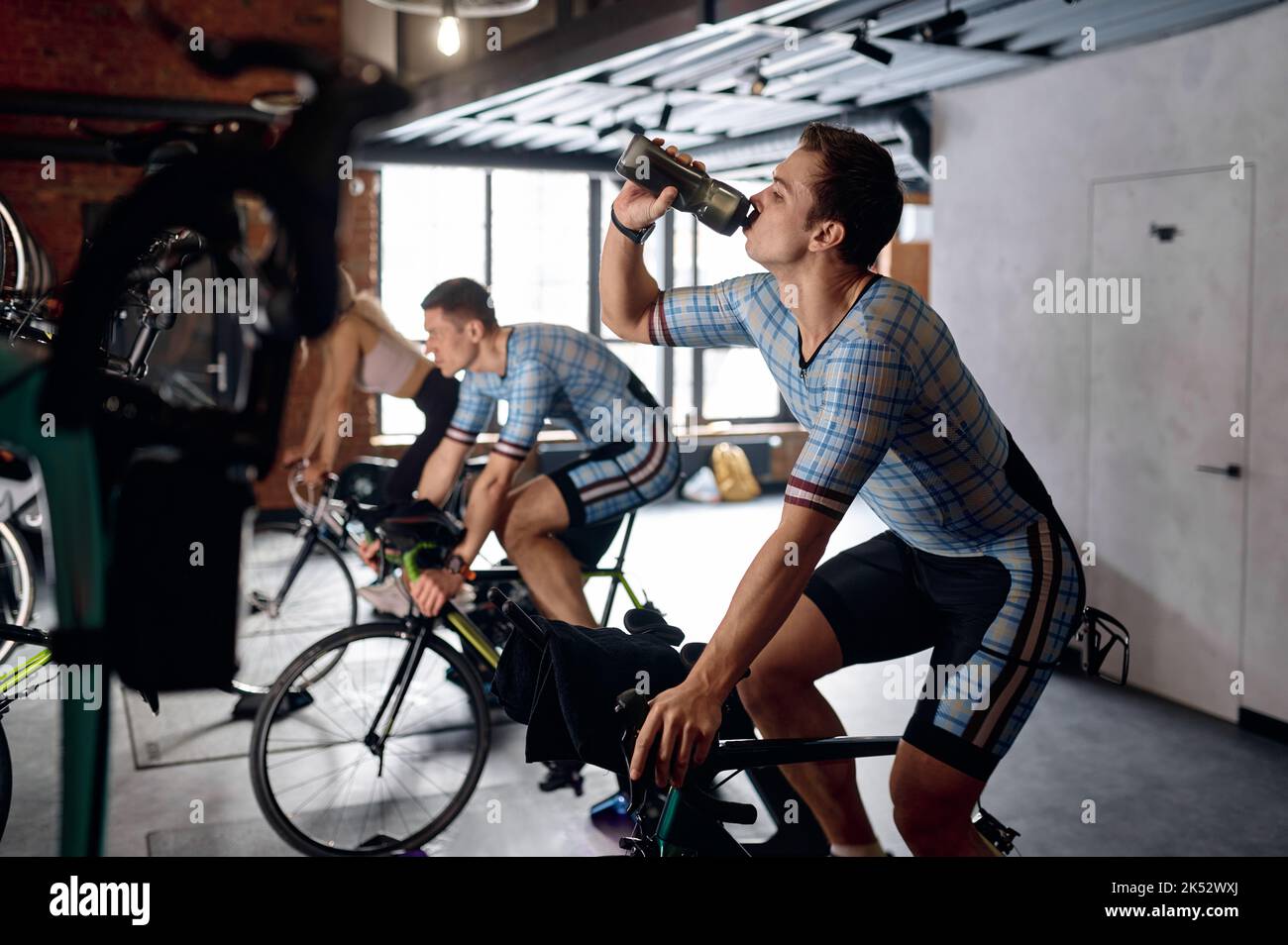 Sportsman drinking water training on stationary bike Stock Photo - Alamy