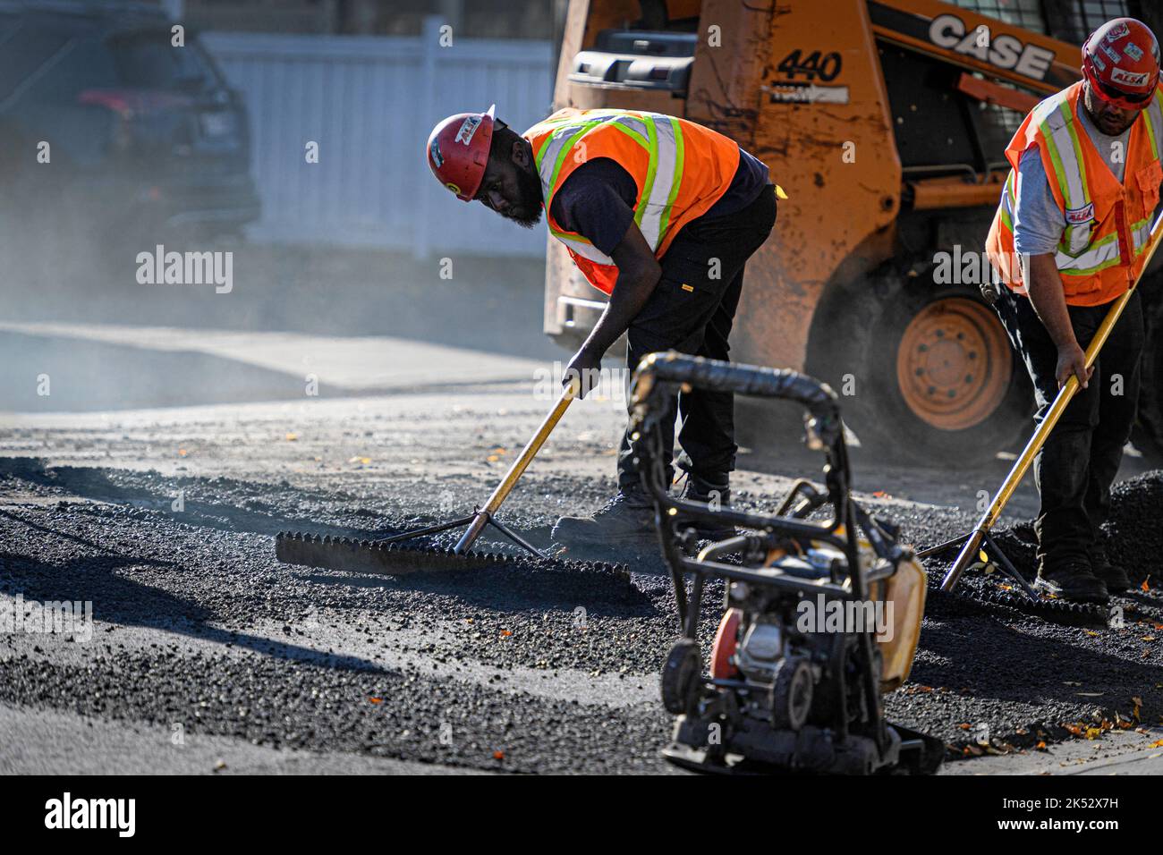 A road or street paving crew working to repair an asphalt surface using ...