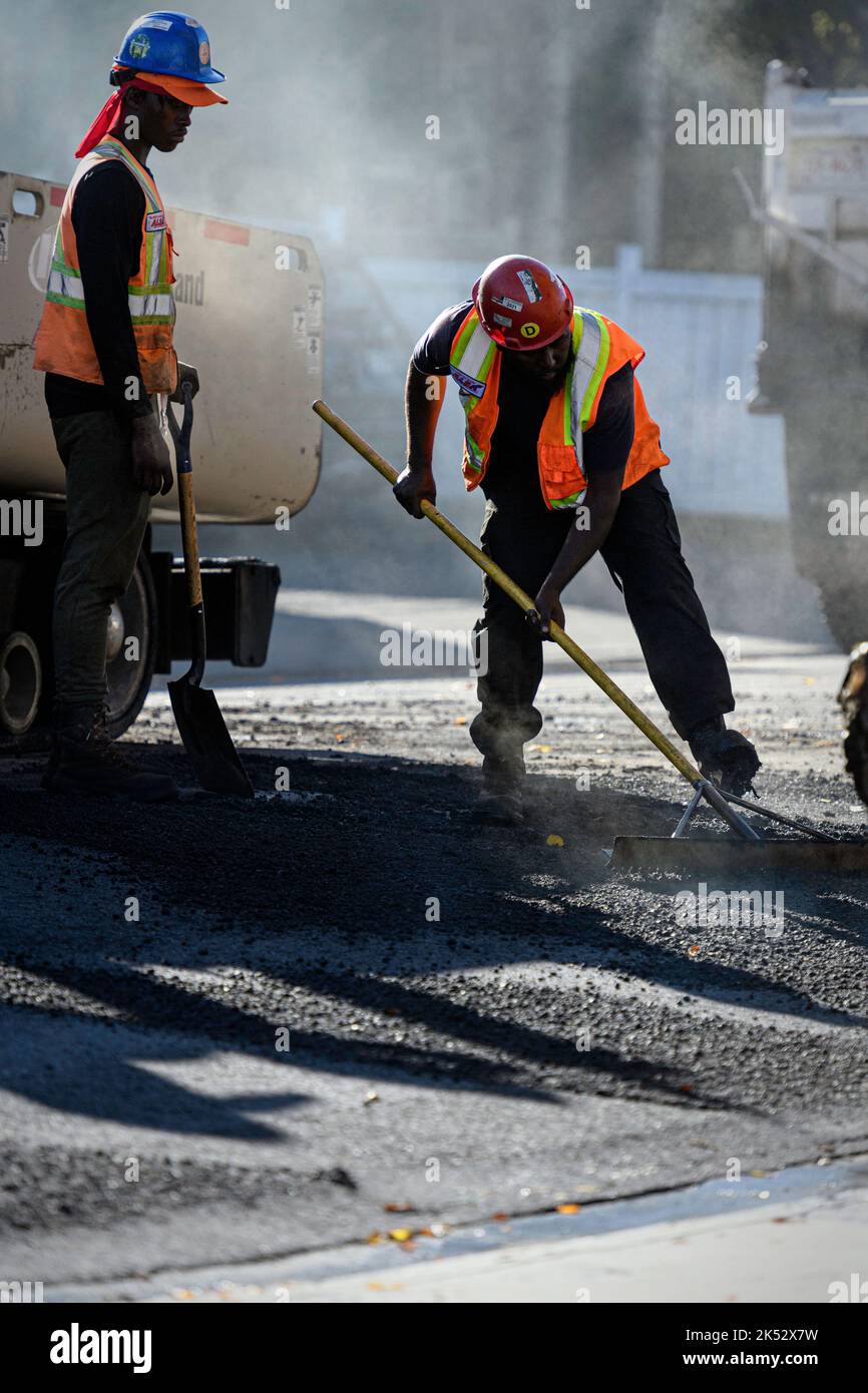 A road or street paving crew working to repair an asphalt surface using ...