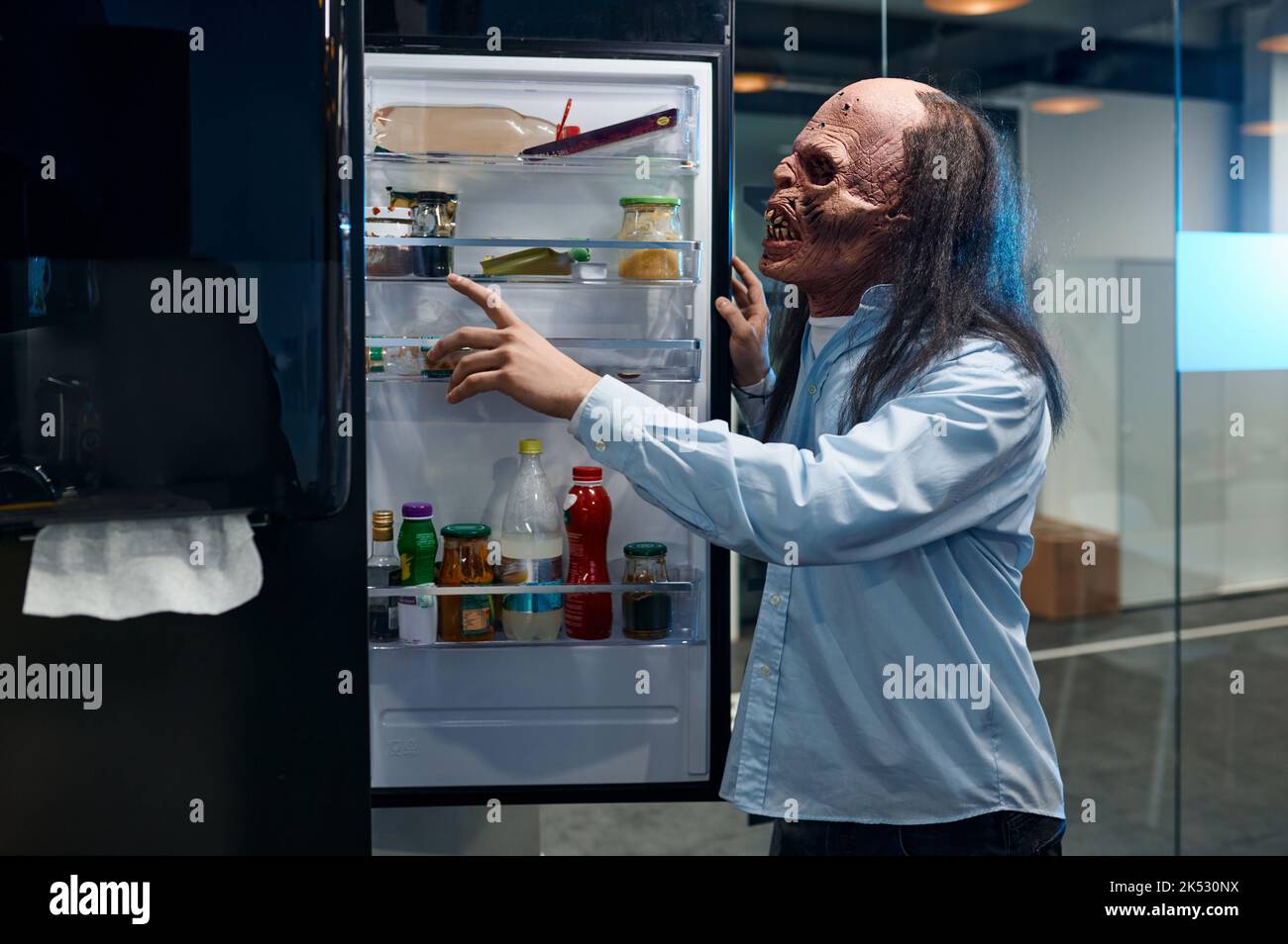 Creepy zombie employee looking for food in fridge Stock Photo - Alamy