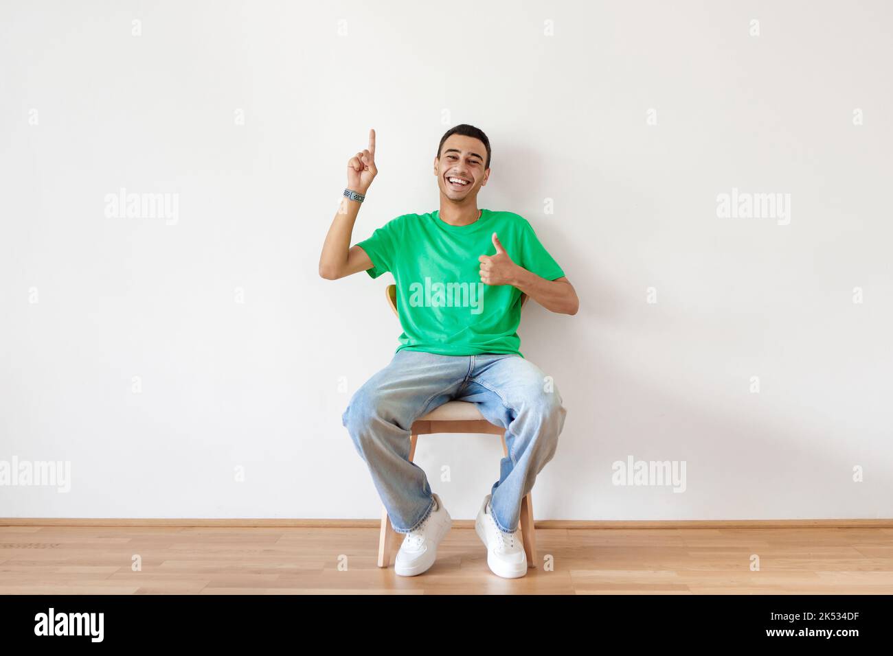 Excited middle eastern guy gesturing thumbs up and pointing finger up ...