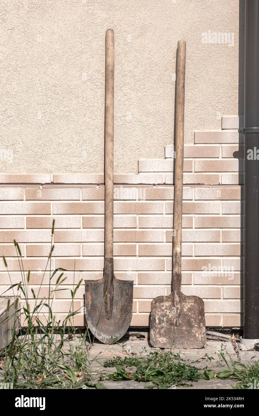 Two dirty filthy shovels against the tile wall summer day, spade Stock ...
