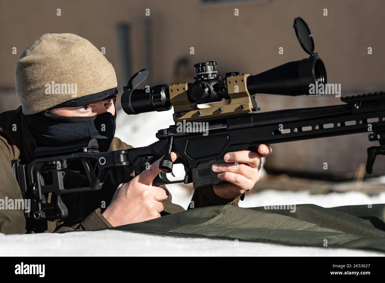 A sniper rifles with an optical sight in man`s hands closeup aiming ...