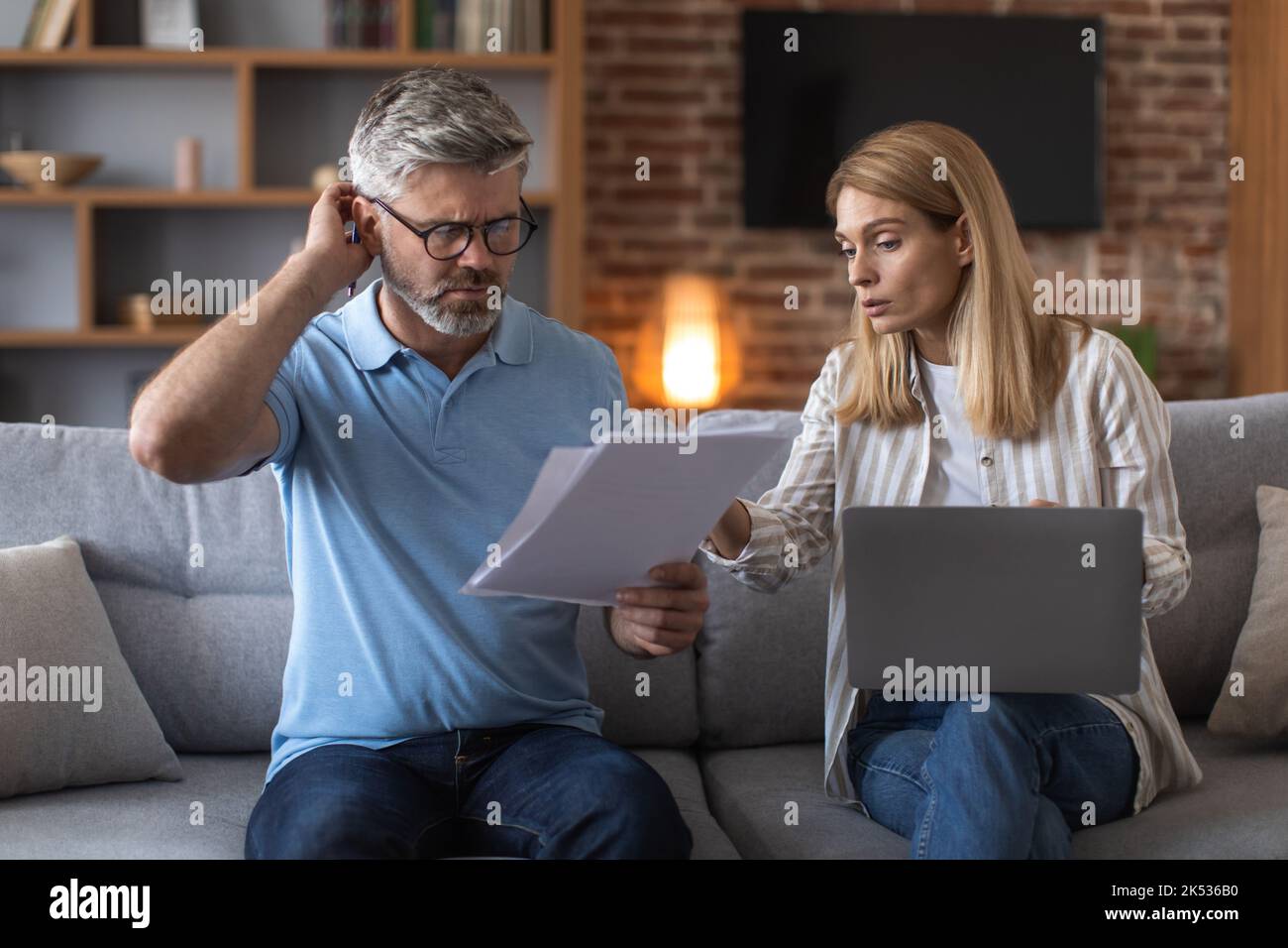 Sad mature caucasian male and female work with documents and pc, pay ...