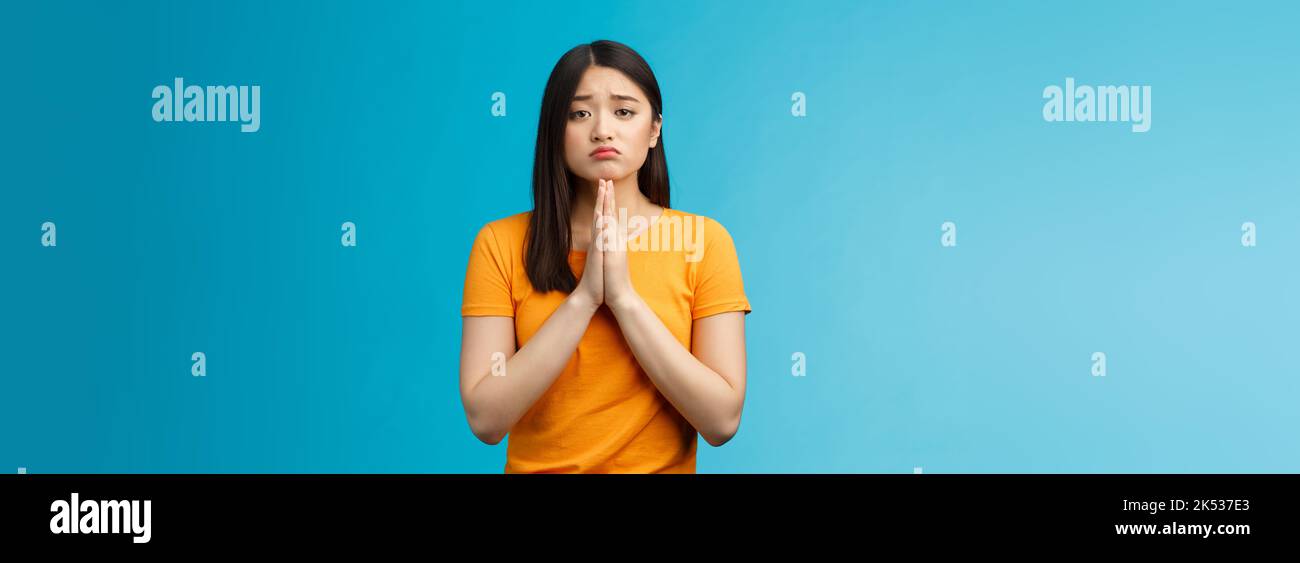 Upset cute silly asian girl praying, plead for help, pouting frowning ...