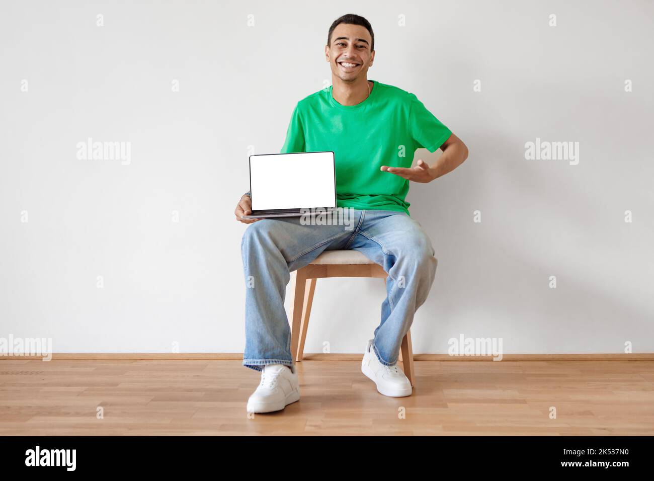 Excited arab guy showing laptop with white empty screen, sitting on ...