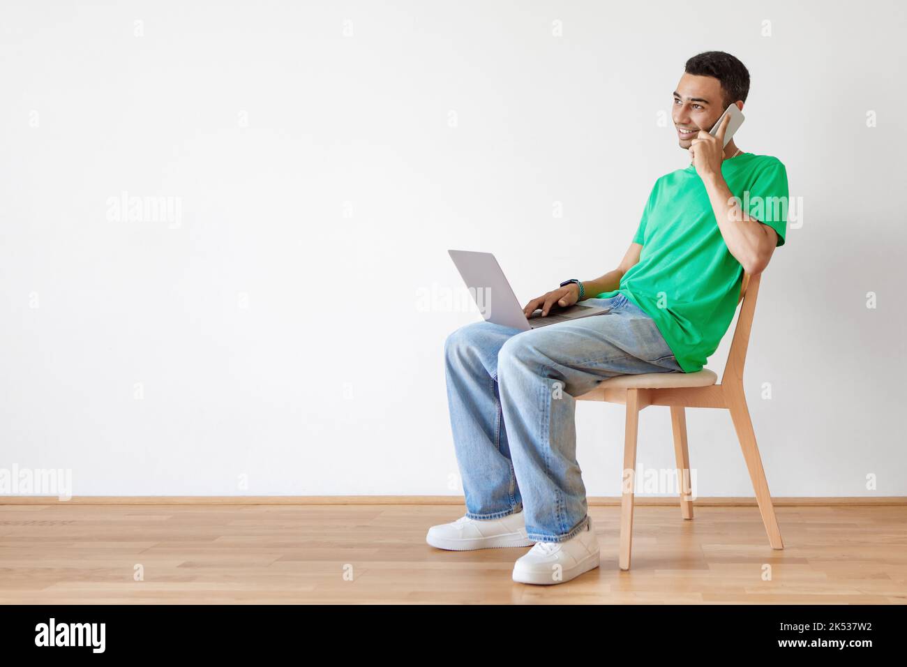 Positive arab man sitting on chair with computer on his lap, having ...