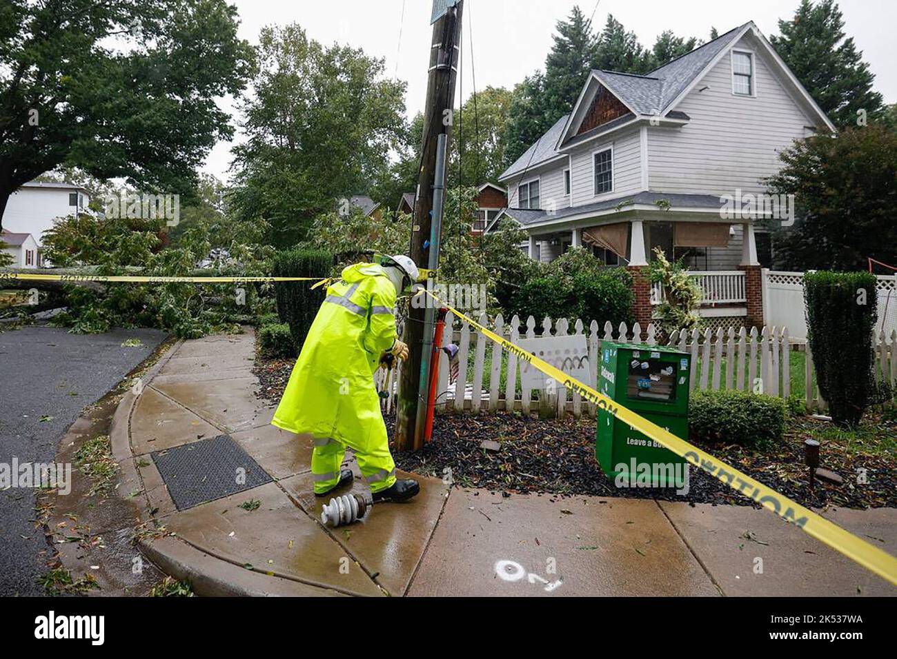 A Duke Energy employee examines an electricity pole near a fallen tree ...