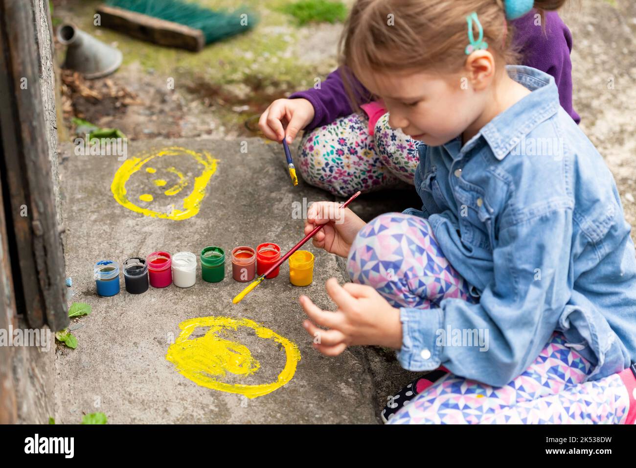Young children painting on concrete, two girls, art, outdoor activity ...