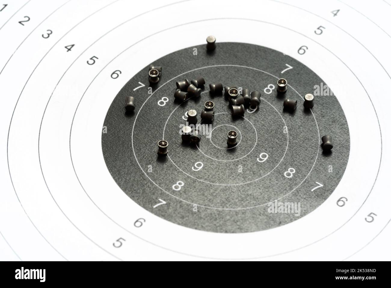 Circle shooting target and lots of metal pellets laying on top, object ...