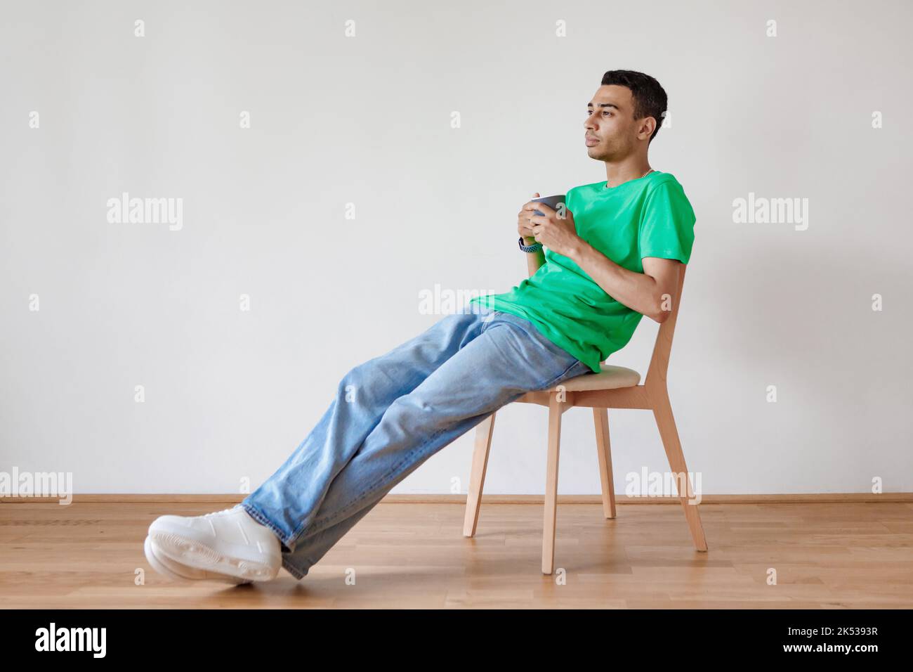Rest concept. Pensive arab guy drinking coffee, sitting on chair over ...