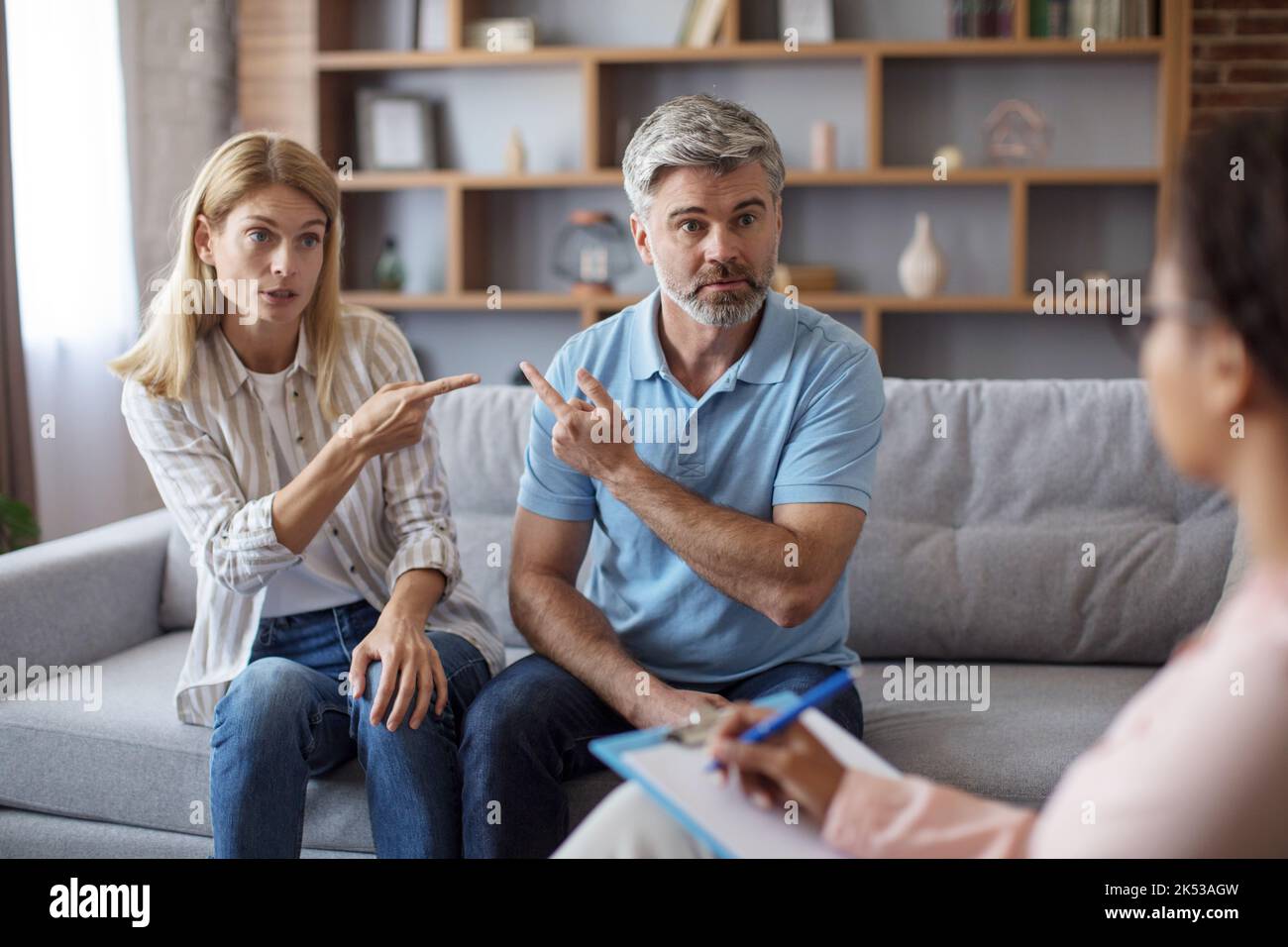 Sad mature caucasian lady and male point fingers at each other in ...