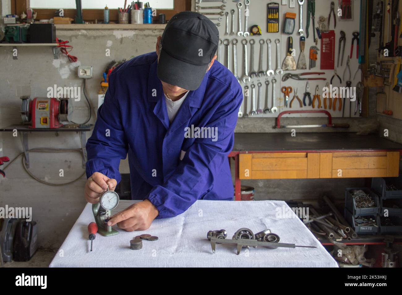 Picture of a mechanic in his workshop taking measurements with a ...