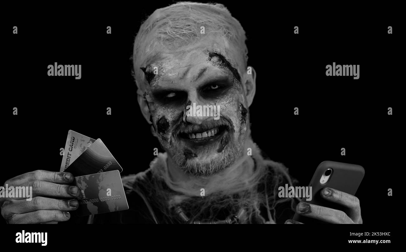 Sinister man with horrible scary Halloween zombie make-up using credit ...