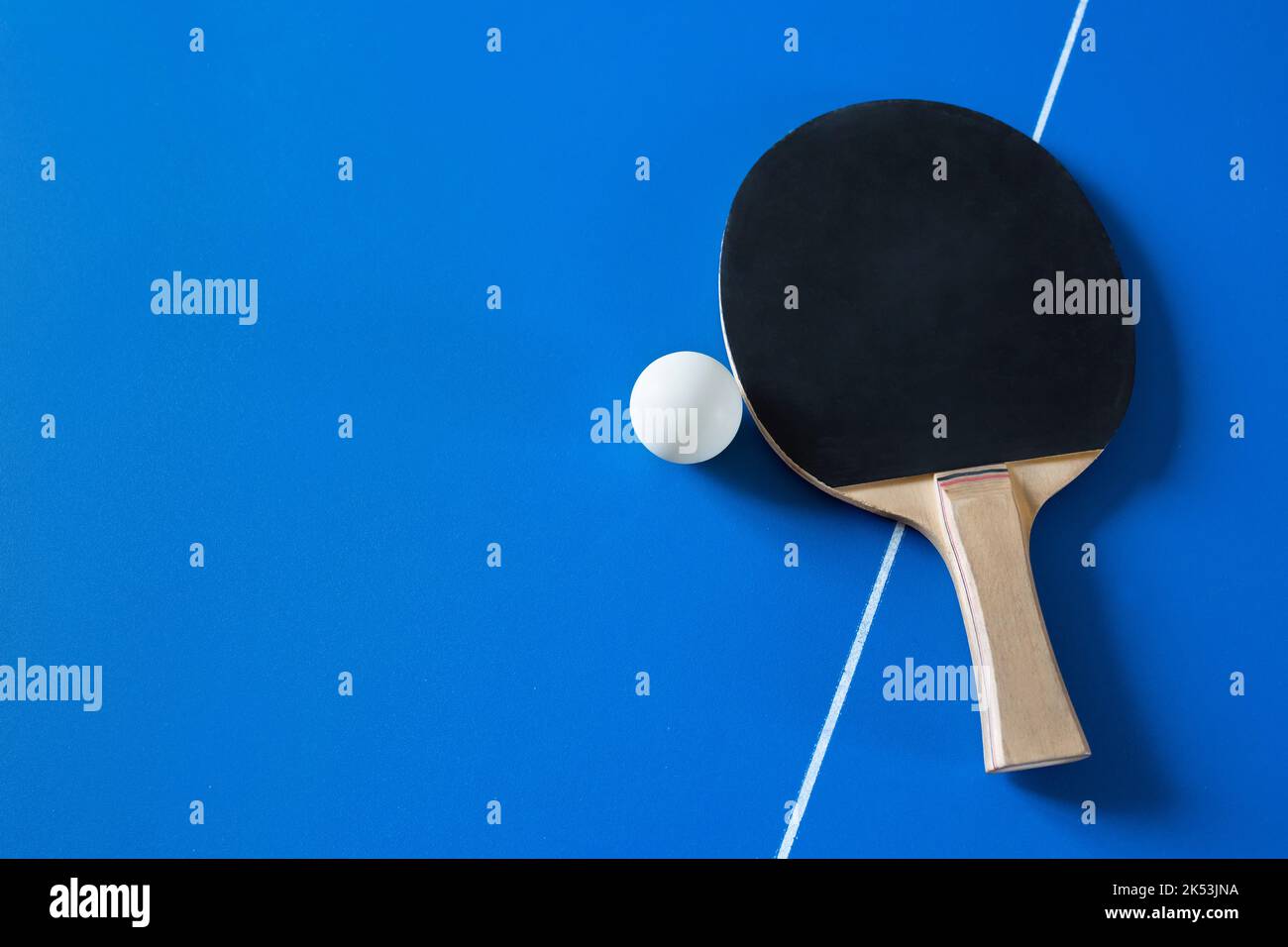 A racket for table tennis with a ball lying on the blue table. A view ...