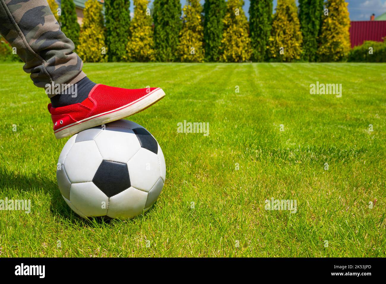 A football ball and child leg at the background of a house backyard on ...