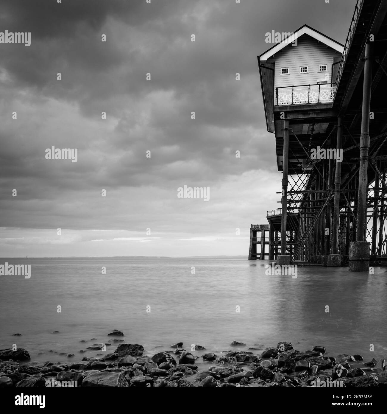 A scenic grayscale of a tranquil seascape and a wooden house by the ...