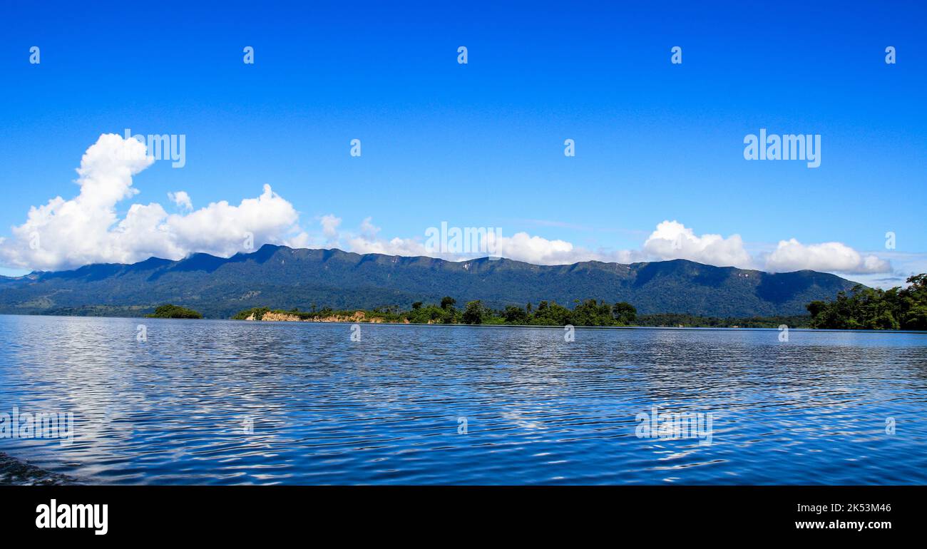 A scenic landscape of a clean blue sea with mountains in the background ...