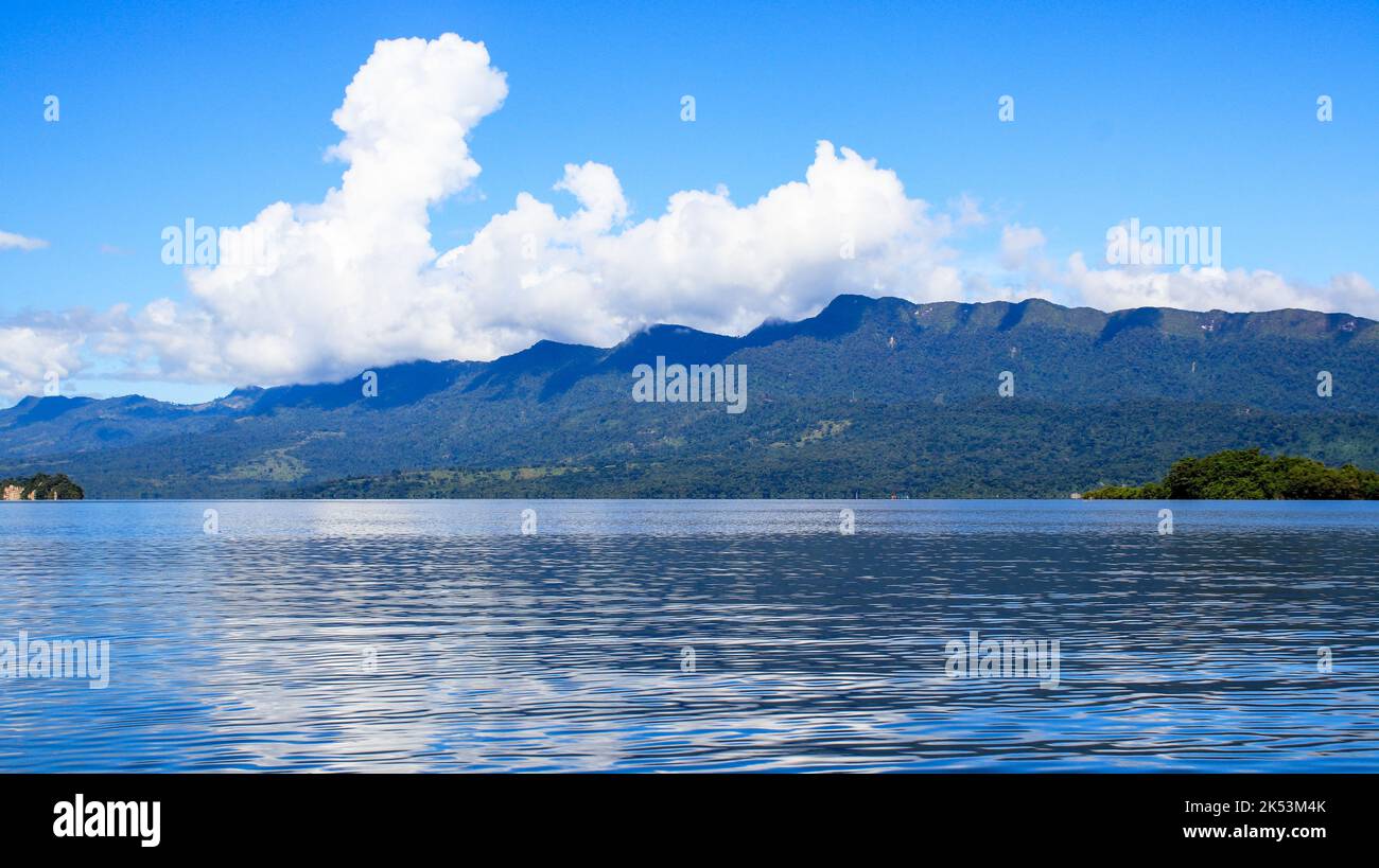 A scenic landscape of a clean blue sea with mountains in the background ...