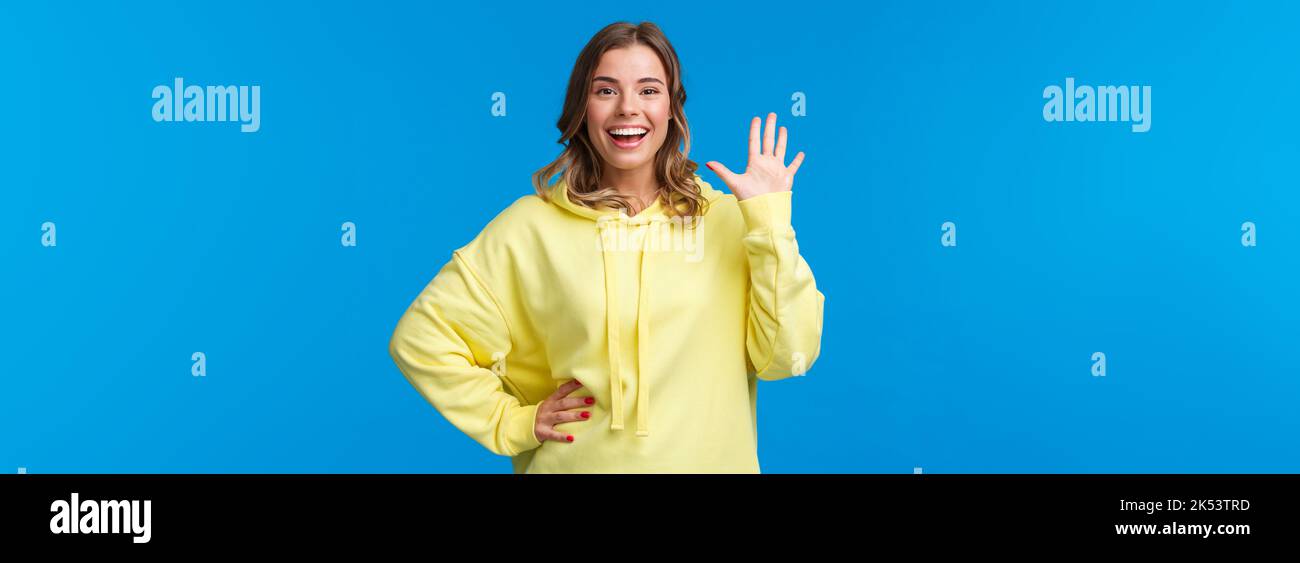 Cheerful friendly outgoing blond girl waving hand, informal greeting ...