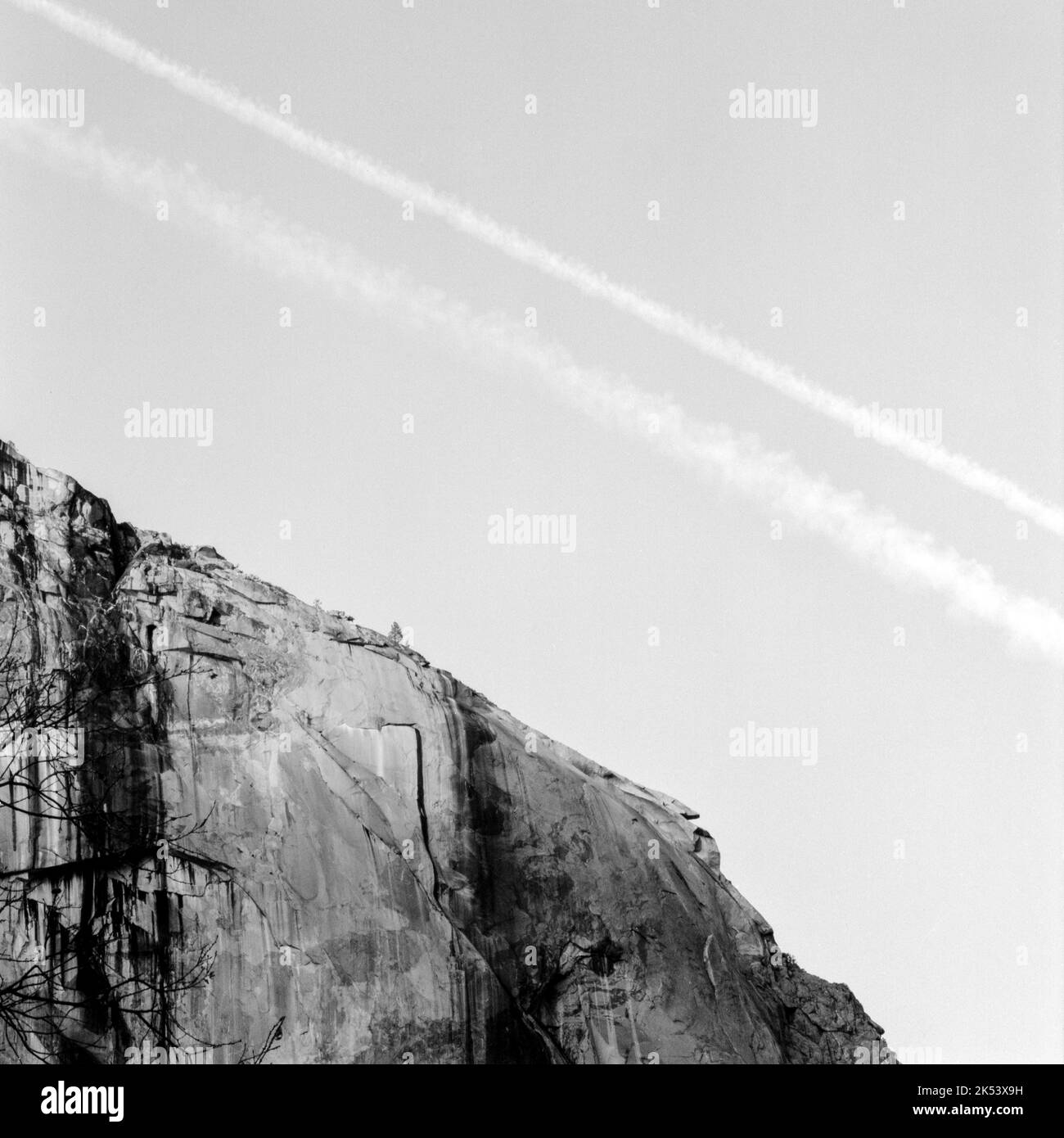 A grayscale shot of jet trails over a rock face in Yosemite National ...