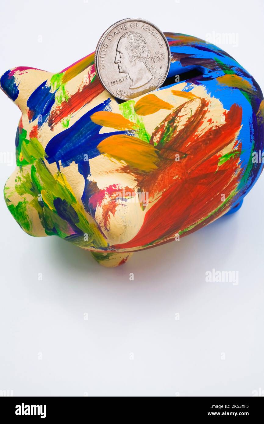 US twenty-fiive cent coin on top of multicolored painted piggy bank ...