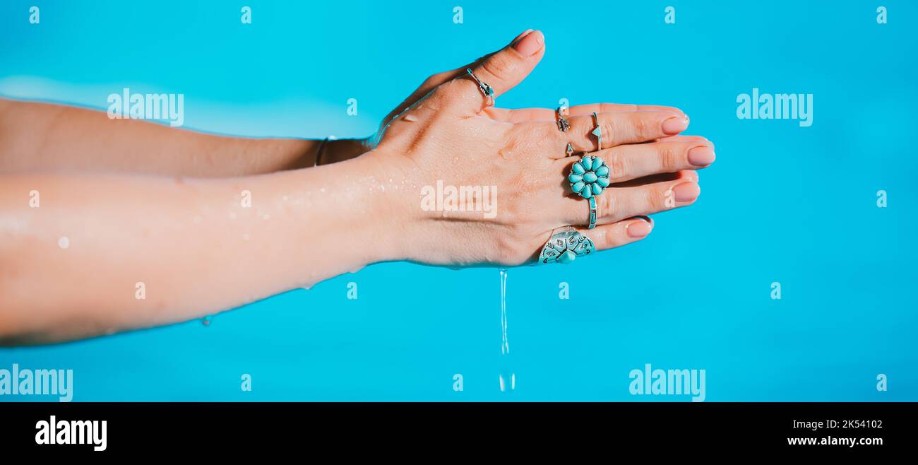 Priestess woman pours out clean water. Palms with gypsy boho rings ...