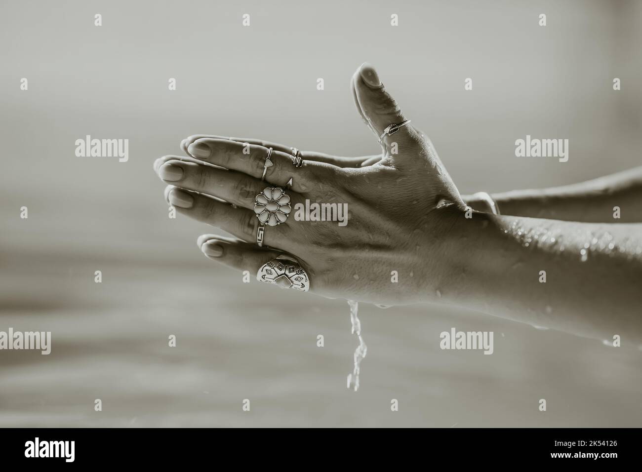 Priestess woman pours out clean water. Palms with gypsy boho rings ...