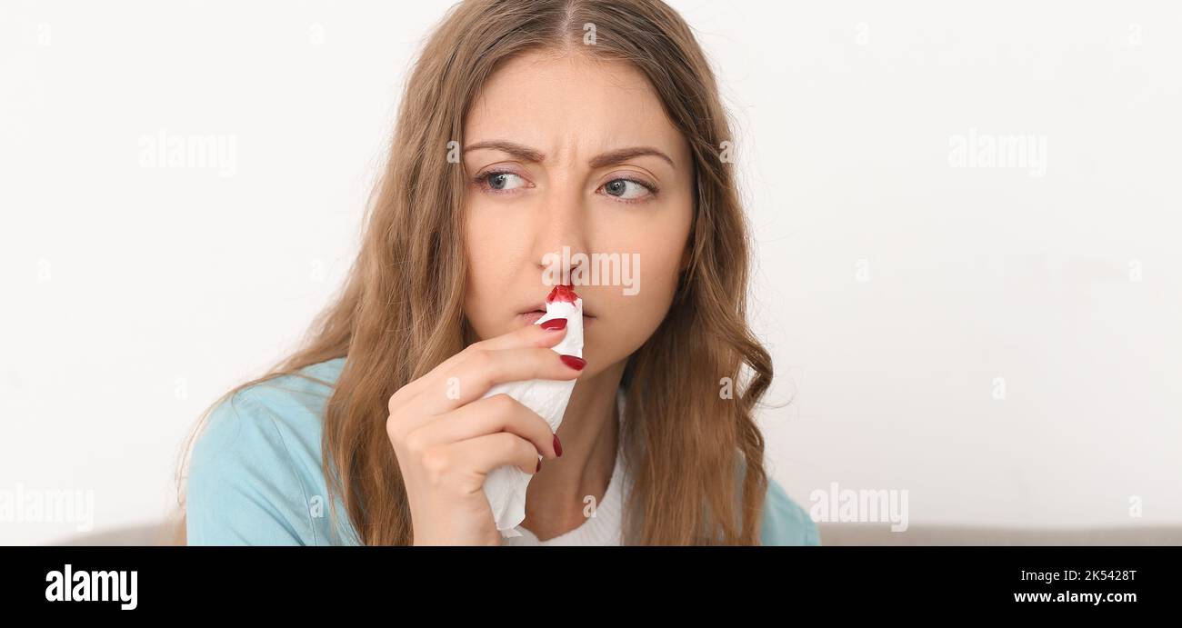 Young woman wiping nosebleed with tissue at home Stock Photo - Alamy