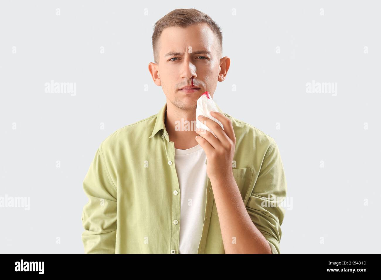 Young man with nosebleed and tissue on white background Stock Photo - Alamy