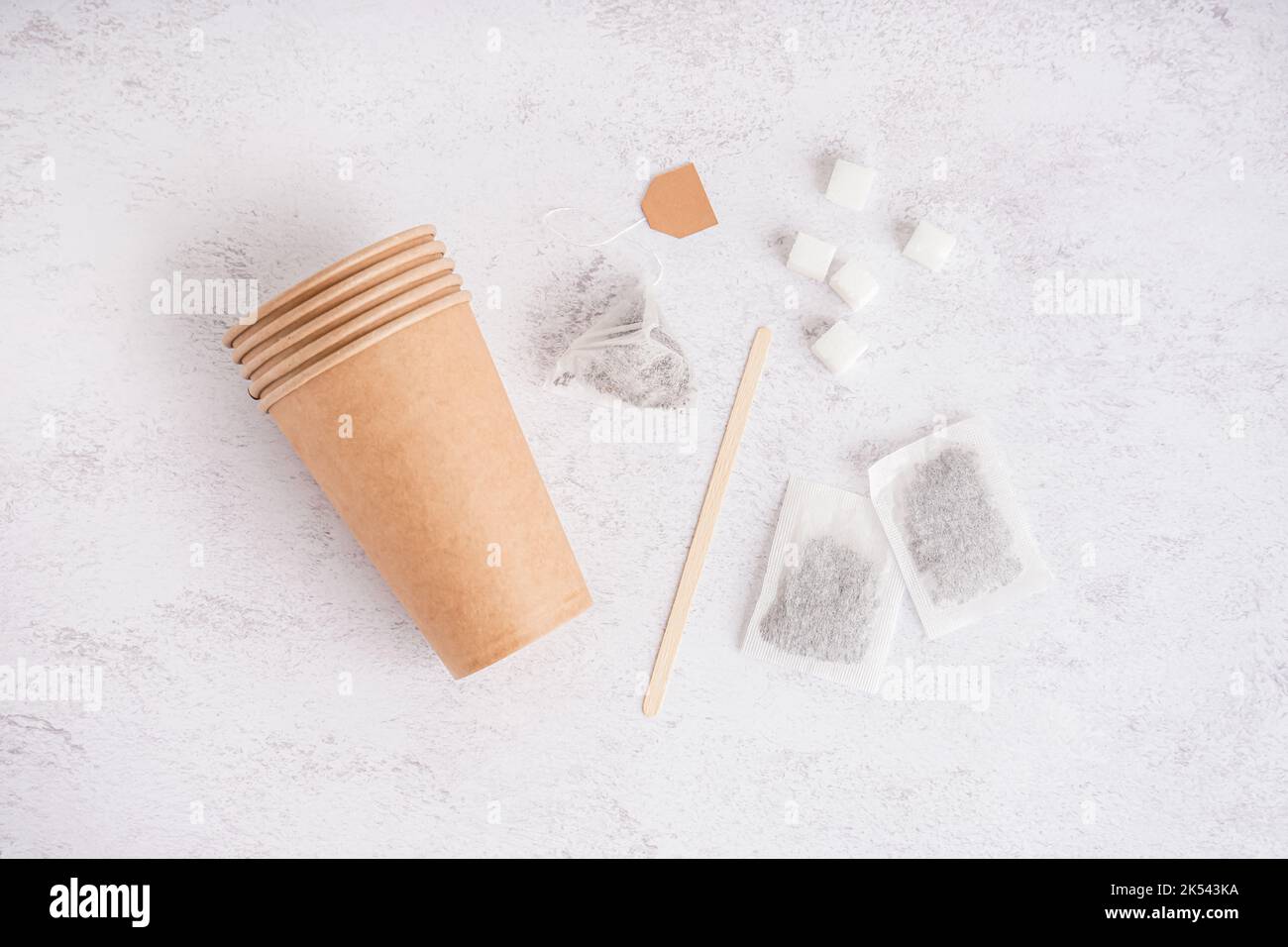 Paper cups, stick, tea bags and sugar on light background Stock Photo ...