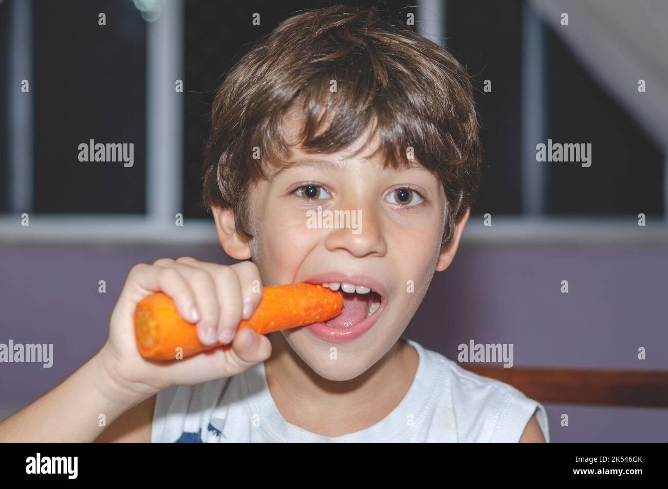 Happy little boy eating a fresh carrot and having fun. Healthy ...