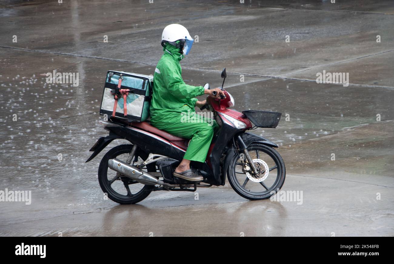 Man with a delivery box on a motorcycle ride in the rain Stock Photo ...