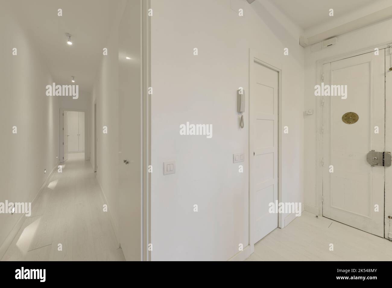 Hallway of an empty urban dwelling with light wood floors and off-white ...