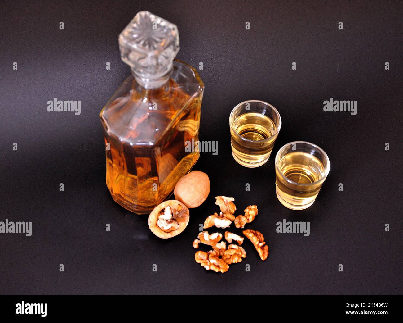 Walnut liqueur in a bottle and two glasses on a black background, next ...