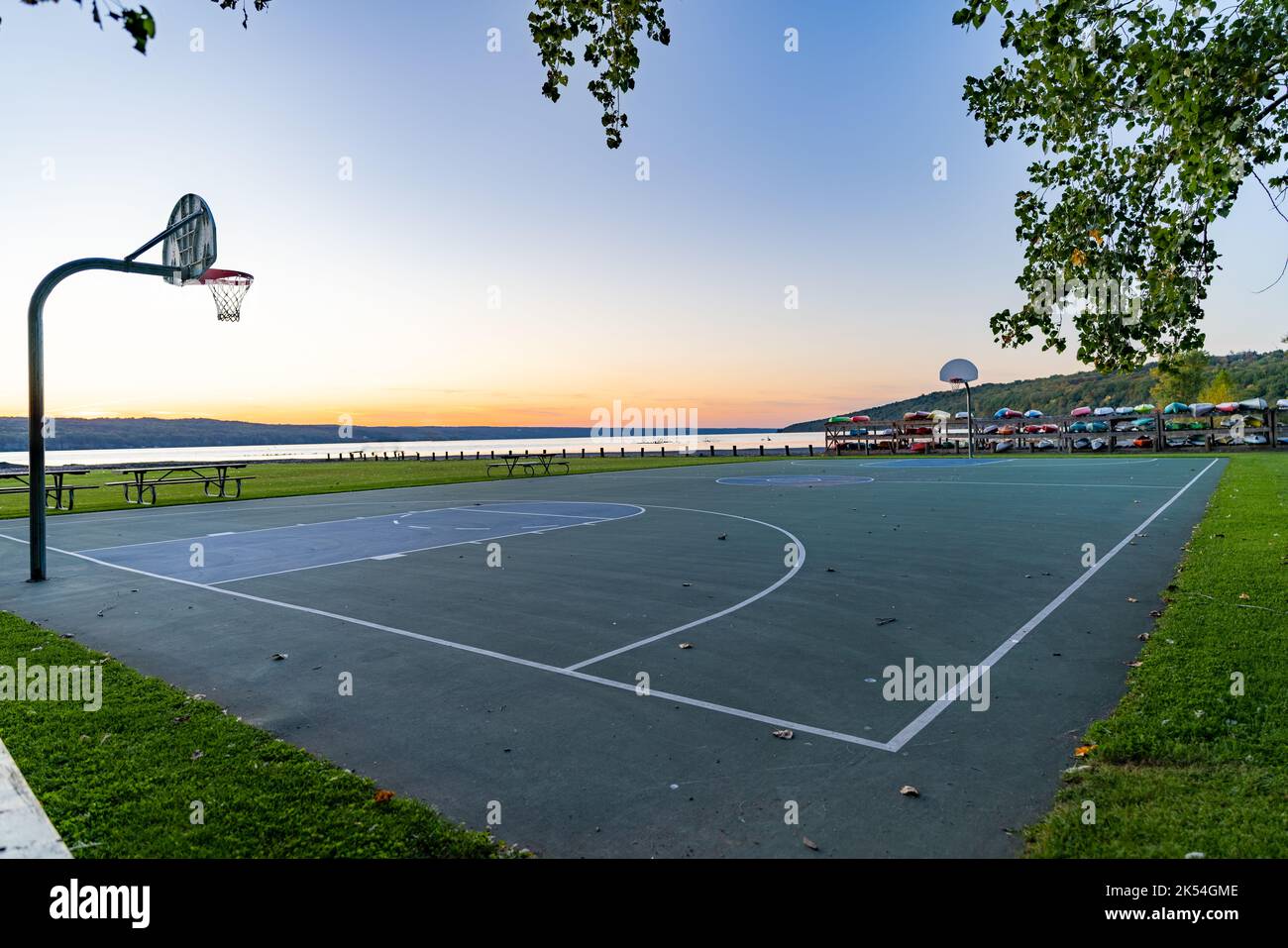 Late afternoon photo of a lake side blue and green outdoor basketball ...