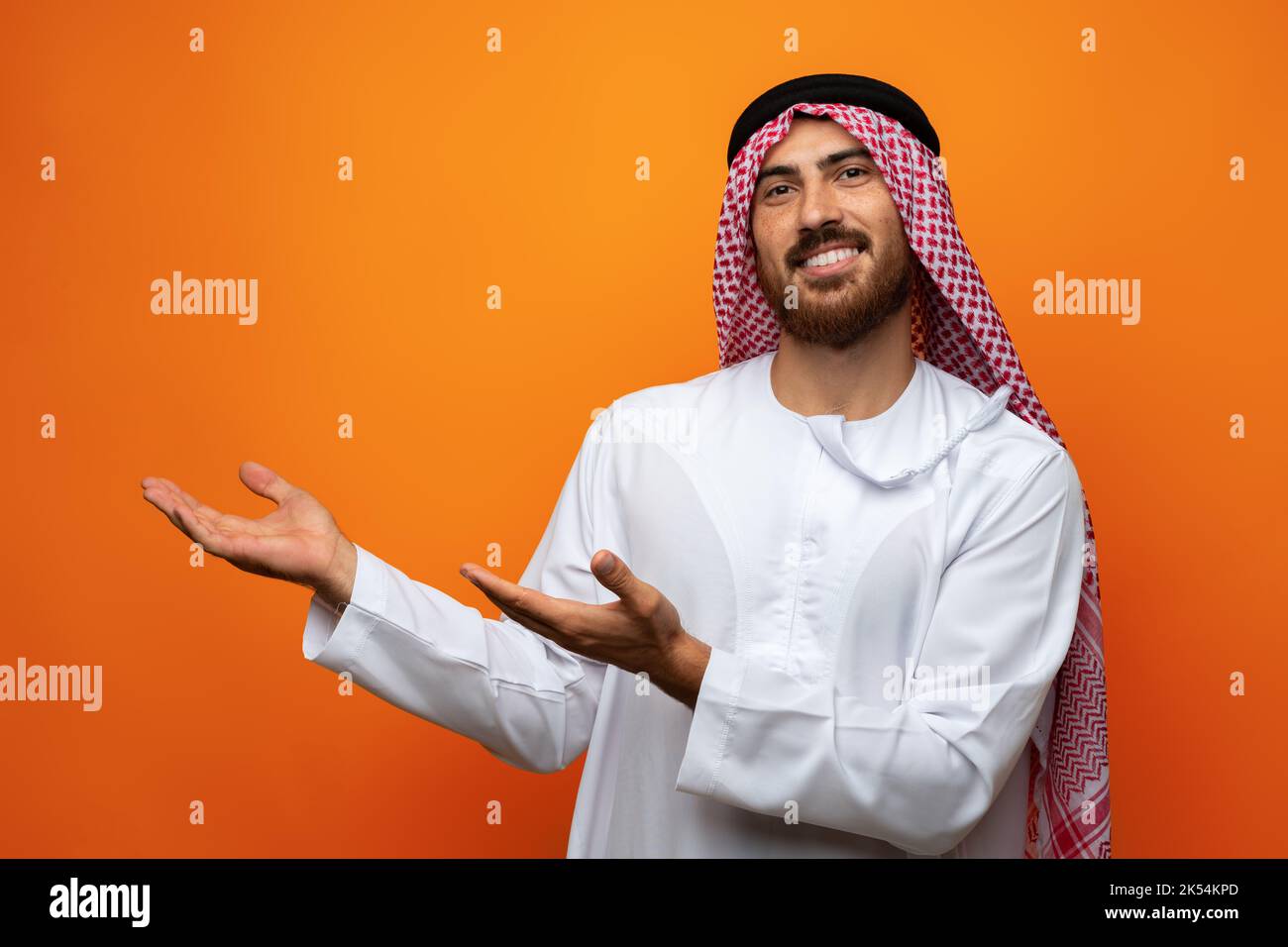 Young Arab man pointing hand to copy space on orange background Stock ...