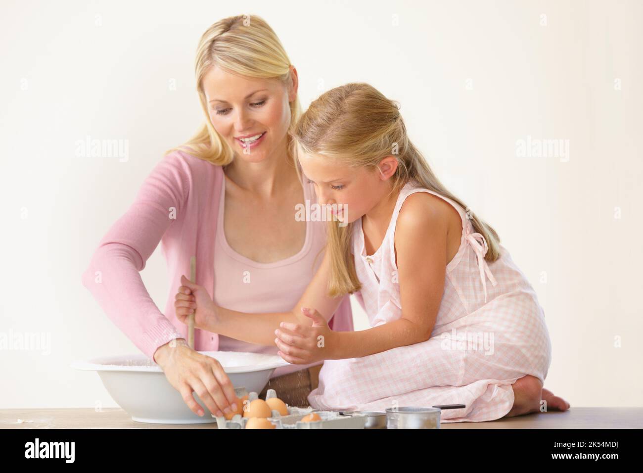 Creating something yummy together. A little girl kneeling on a kitchen ...