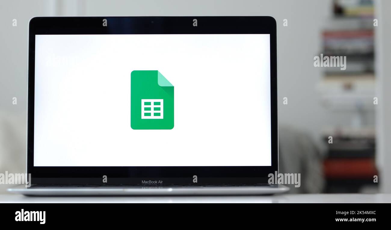 A logo design of google sheets on a laptop screen in blurred background ...